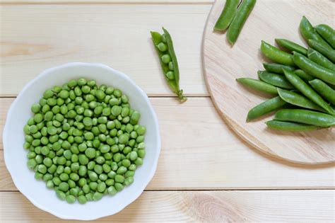 나무 테이블에 흰색 접시에 신선한 식용 껍질을 벗긴 녹색 완두콩과 부엌 책상에 전체 포드 0명에 대한 스톡 사진 및 기타 이미지 0명 건강한 생활방식 건강한 식생활