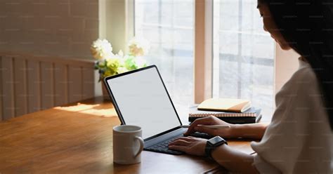 편안한 거실을 배경으로 현대적인 나무 테이블에 앉아 흰색 빈 화면 컴퓨터 노트북의 키보드에 입력하는 웹 사이트 관리자로 일하는 창의적인 여성 사진 Unsplash의