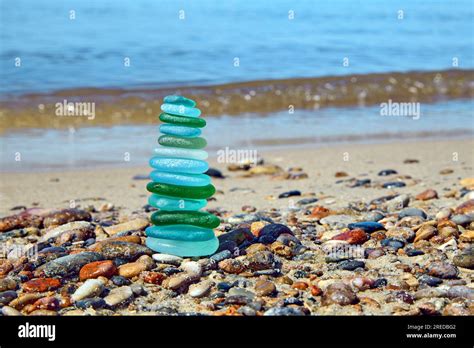 Balanced Pyramid Of Glass Bottle Fragments Polished By Sea On Shore Of Sandy Pebble Beach Stock