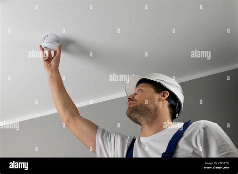 Fire Safety Engineer Installing Photoelectric Smoke Detector On House