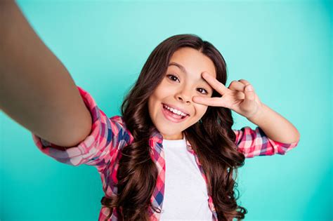 밝은 생생한 빛이 녹색 파란색 청록색 배경 위에 고립 된 V 기호를 보여주는 체크 셔츠를 입고 좋은 매력적인 매력적인 귀여운