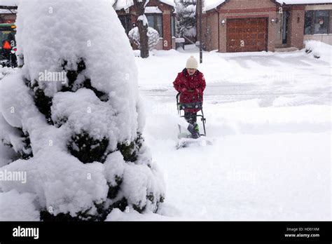 Woman Using Eco Friendly Snow Plow Is Plowing Her Driveway In The