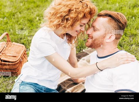 Side View Of Happy Redhead Couple Smiling Together At Picnic In Park