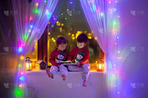 两个孩子在窗户上玩平板电脑