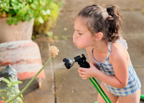 Premium Photo Young Girl Is Watering Plants In The Backyard While
