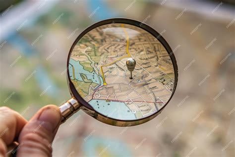 a hand holding a magnifying glass over a pin location map indicating