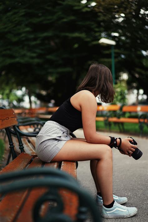 Mujer Con Camiseta Sin Mangas Negra Y Pantalones Cortos Blancos Sentada