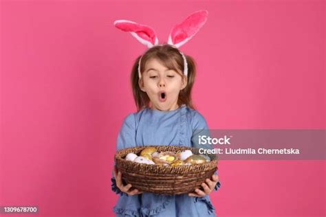 분홍색 배경에 부활절 달걀의 전체 고리버들 바구니를 들고 토끼 귀와 놀란 어린 소녀 부활절 달걀에 대한 스톡 사진 및 기타