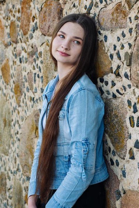 Portrait Of A Long Haired Girl In A Denim Jacket Against A Stone Wall Stock Photo