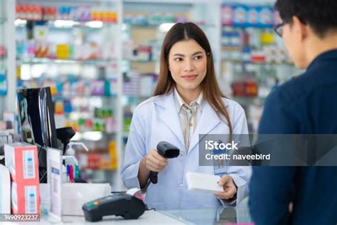 아시아 여성 약사가 약국에서 바코드 판독기 스캔 알약 상자를 들고 있다 의약품 및 건강 관리 제품이있는 선반 건강관리와 의술에