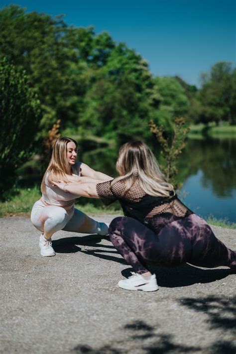 Two Women Exercising Outdoors In A Green Park Setting Together Stock
