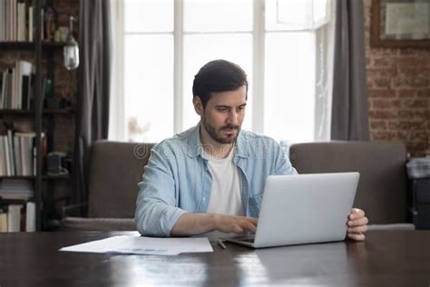 Serious Man In Office Working With Databases Using Laptop And Excel
