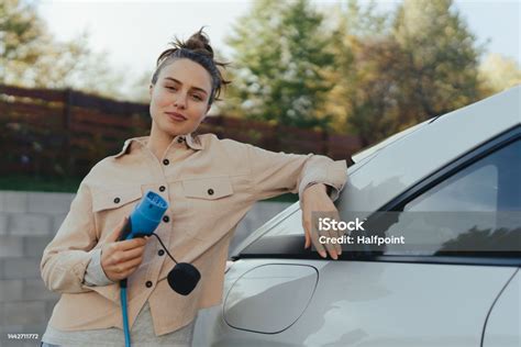 전기 자동차에서 전원 공급 장치 케이블을 들고 집에서 충전할 준비를 한 젊은 여성 지속 가능하고 경제적인 교통 개념 전기 자동차 대체 연료 자동차에 대한 스톡 사진 및 기타