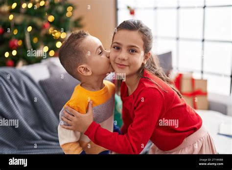 Brother And Sister Kissing And Hugging Each Other Standing By Christmas