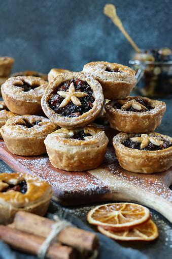 나무 도마에 배치 홈메이드 다진 파이 더미의 클로즈업 이미지 다진 고기로 가득 바삭바삭한 페이스트리 아이싱 설탕 계피 스틱 번들 달콤한 다진 항아리 전경에 초점을 맞춘 별