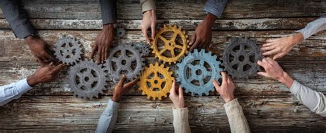 The Collaborative Teamwork Of Diverse Hands Arranging Interlocking Gears On A Tableai