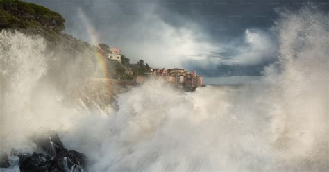큰 파도가 해안에 부딪히고 집이 배경으로 있습니다 사진 Unsplash의 텔라로 이미지