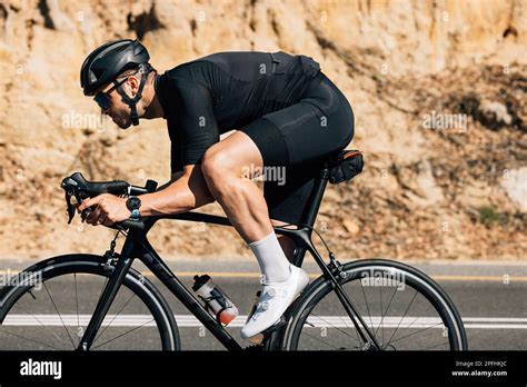 Professional Cyclist In Black Sportswear Riding Road Bike Against The