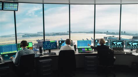 현대 공항 타워에서 일하는 다양한 항공 교통 관제 팀 사무실 방은 내비게이션 화면 비행기 출발 및 컨트롤러도착 데이터가있는 데스크톱 컴퓨터 디스플레이로 가득합니다 배차원에