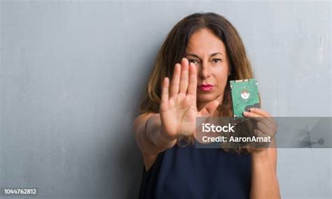 중세 스페인 여자 회색 그런 지 벽 오픈 손으로 심각 하 고 자신감 표현 방어 제스처 정지 표시를 하 고 하드 드라이브를 들고 서 갈색 머리에 대한 스톡 사진 및 기타