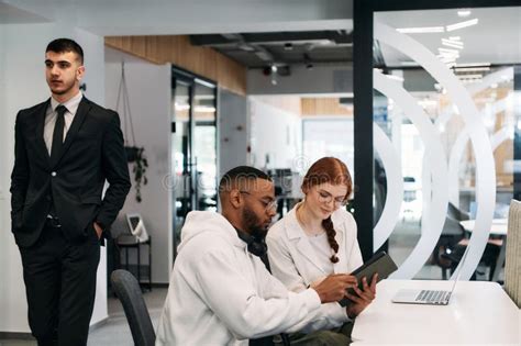 Two Colleagues Collaborating In A Modern Office While Discussing A