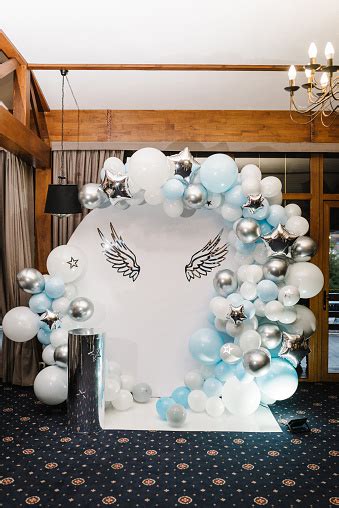 침례를위한 아치 파란색 풍선의 배경에 천사 날개가 있는 사진 영역 실버 스타일의 사진 영역 베이비 샤워 생일 파티 개념 장식 축하 세례 개념입니다 트렌디 한 장식 아치