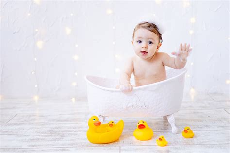 6 개월의 즐거운 아기 소녀는 거품과 고무 오리가있는 욕조에서 목욕하고 있으며 작은 아이는 물놀이 보살핌과 위생의 개념으로 재미있게 놀고 있습니다 6 11 개월에 대한 스톡