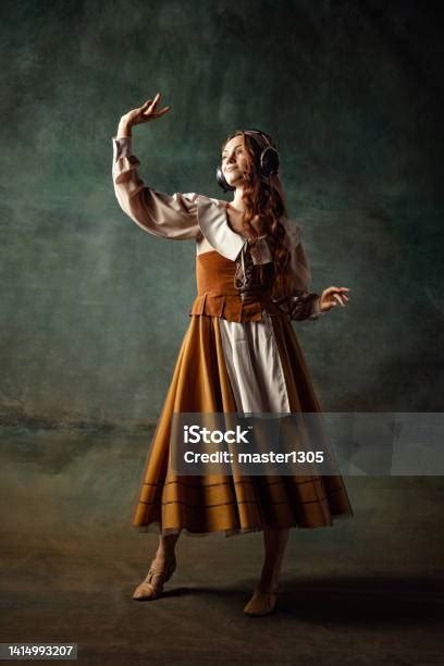 빈티지 스타일 어두운 배경에 고립 된 르네상스 시대의 소녀처럼 긴 곱슬 머리를 가진 젊은 매력적인 빨간 머리 소녀 시대 비교 아름다움 예술 그림 중세에 대한 스톡 사진 및