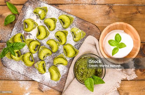 토르텔리니 E 토르텔로니 전형적인 요리 에밀리아 이탈리아 수제 생 이탈리아 어 토르텔로니와 나무 배경에 녹색 페스토 재료와 음식 배경 높은 각도 보기 공간을 복사합니다 0