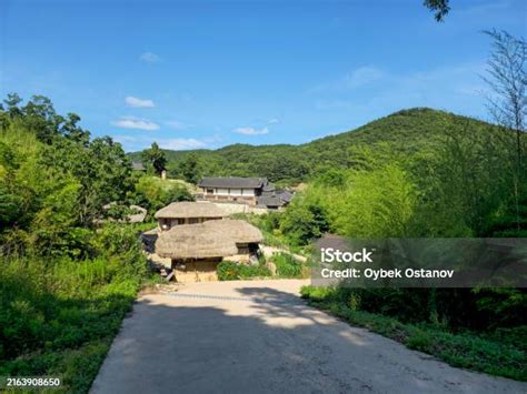 비포장 도로와 주택이 있는 시골 지역 집들은 짚으로 만들어졌으며 서로 밀집되어 있습니다 하늘은 파랗고 구름은 없습니다 산에 대한