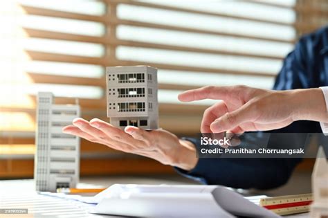 건축가 또는 엔지니어 작업자로 구성된 팀이 사무실에서 건물 모델을 가지고 작업하고 건물 레이아웃을 검사하고 건설 프로젝트를 계획하고 새로운 아이디어를 함께 검색하는 이미지를