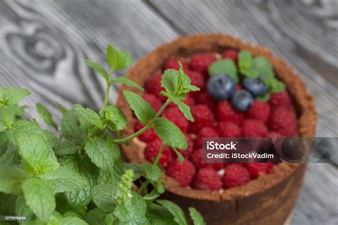 크림 치즈를 곁들인 초콜릿 케이크를 굽지 않습니다 라즈베리 블루베리 민트 잎으로 장식되어 있습니다 근처에는 성장하는 민트냄비가