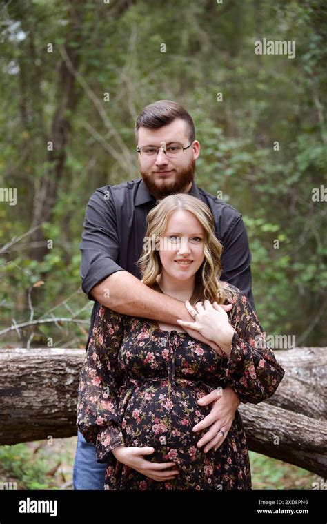 A Pregnant Couple Embracing In A Forest With The Mans Arms Aro Stock