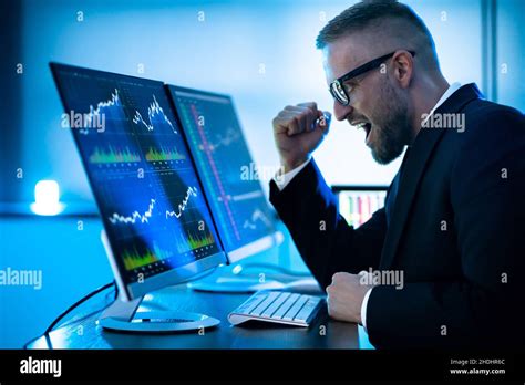 Successful Stock Market Trader Looking At Graphs On Multiple Screens In