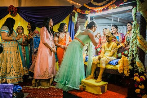 Happy Indian Groom Sitting On Couch In Decorated Room With Women During