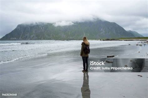 배낭을 멘 젊은 여자가 빈 모래 해변을 따라 걷는다 마을과 산 아름다운 자연 풍경 외로운 소녀 방랑벽 여행 모험 라이프 스타일 노르웨이 북부 탐험 걷기에 대한 스톡 사진 및