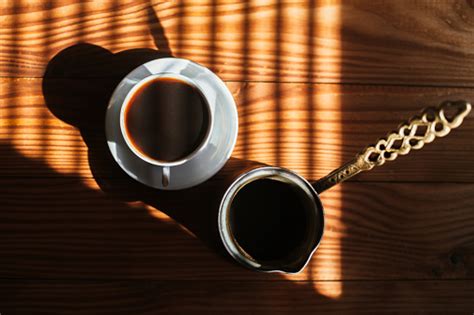 전통적인 구리 터키 커피 포트와 아침에 나무 테이블에 접시에 흰색 도자기 컵에 뜨거운 신선한 향기로운 커피 최고 전망 고급