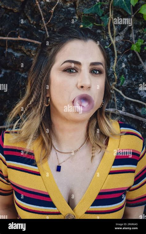 Young Caucasian Woman Blowing Bubble Gum Into A Balloon Shape Playful And Carefree Moment