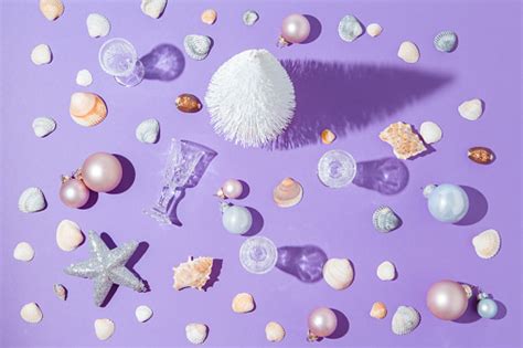 칵테일 안경 크리스마스 공과 바다 껍질이있는 보라색 라벤더 배경에 흰색 가문비 나무 나무 밝고 다채로운 미니멀 아트 구성 크리스마스와 새해 휴일 파티의 개념 개념에 대한