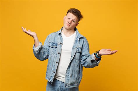 데님 캐주얼 복장에 의아해 화가 젊은 남자의 초상화는 따로 노란 오렌지 벽 배경에 고립 손을 확산 가리키는 사람들은 진심으로 감정 라이프 스타일 개념입니다 복사 공간을 모의