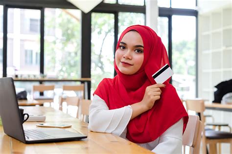 젊은 무슬림 사람들의 초상화 카페 또는 커피숍에서 신용 카드를 보여주는 빨간 히 잡을 착용 하 고 있습니다 쇼핑 온라인 컨셉 개념에 대한 스톡 사진 및 기타 이미지 Istock