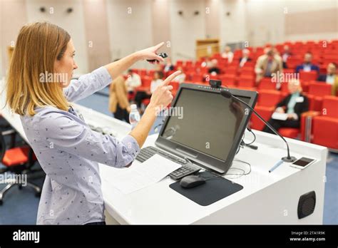 Female Speaker On Panel Answering Question At Business Conference In Convention Center Stock