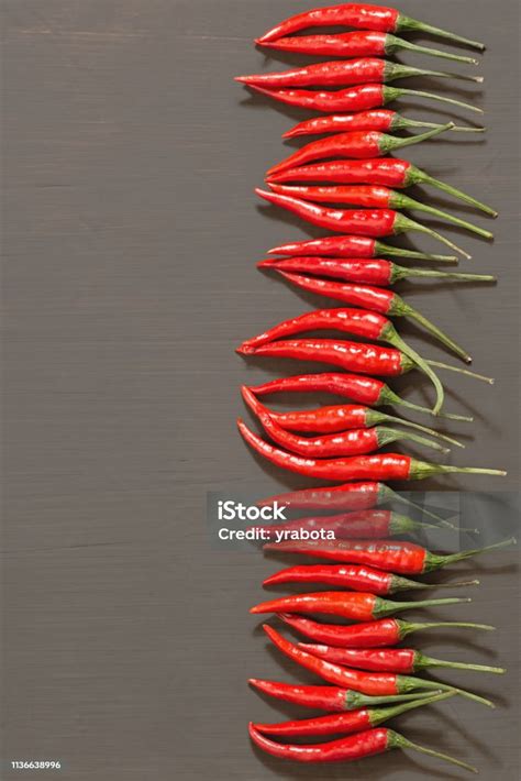 작은 빨간 뜨거운 칠리 고추의 행은 세로로 복사 공간 회색 콘크리트 배경에 배치 평면도 음식 장식입니다 개념에 대한 스톡 사진