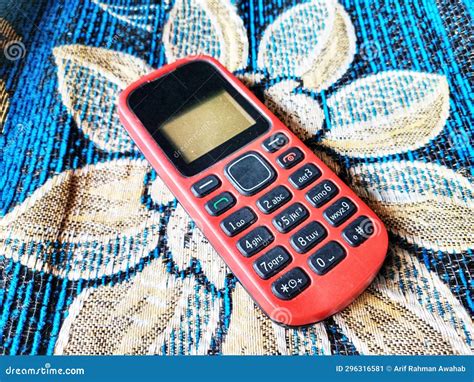 Old Mobile Phone With Texting Or Sms Button Keyboard Or Keypad On Colorful Flowery Fabric