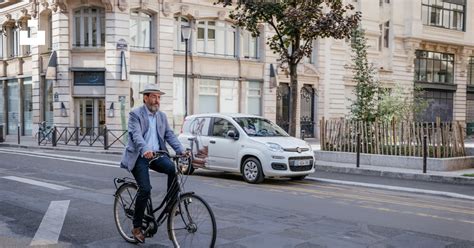 흰색 5도어 해치백 근처에서 검은색 통근 자전거를 타고 있는 남자 사진 Unsplash의 무료 파리 이미지