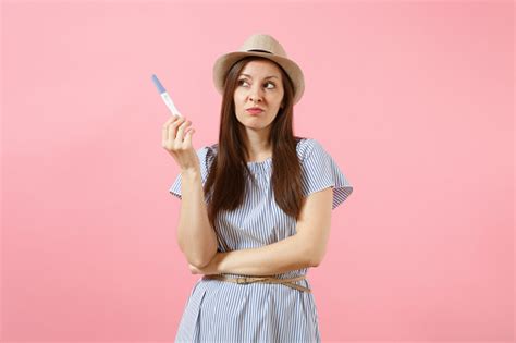 파란 드레스에 슬픈 불행 한 여자 모자 잡고 손 임신 테스트 분홍색 바탕에 고립 된 보고 의료 의료 부인과 임신 임신 출산
