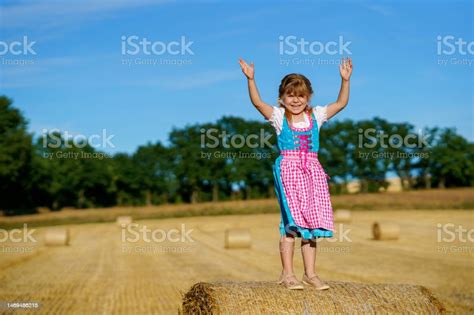 밀밭에서 전통적인 바이에른 의상을 입은 귀여운 어린 소녀 뮌헨에서 옥토버 페스트 동안 건초 더미를 가진 행복한 아이 미취학