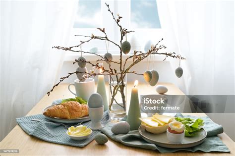 봄 가지 양초 흰색 커튼 복사 공간 선택한 초점이 있는 창 앞에 파란색 회색 장식에 부활절 달걀이 걸려 있는 아침 식사 테이블 부활제에 대한 스톡 사진 및 기타 이미지