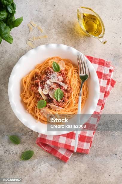 파스타 스파게티 볼로냐세 회색 돌 또는 콘크리트 테이블 배경에 흰색 접시에 볼로냐 소스 토마토 소스 치즈 파르 메산 및 바질과