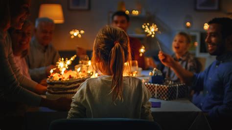 백 뷰 샷 그녀의 케이크에 촛불을 불고 저녁 식사 테이블에서 귀여운 어린 소녀의 생일 축하 테이블에서 행복한 친척과 친구들이 축하하기 위해 모였습니다 아이에 대한 스톡 사진